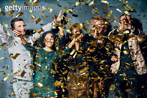 Happy young people dancing and having fun with confetti flying ...