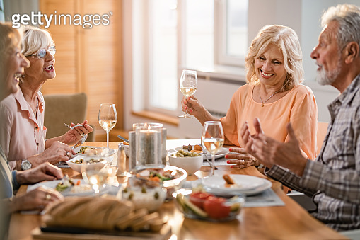 Group of happy senior people talking while eating and drinking wine at ...