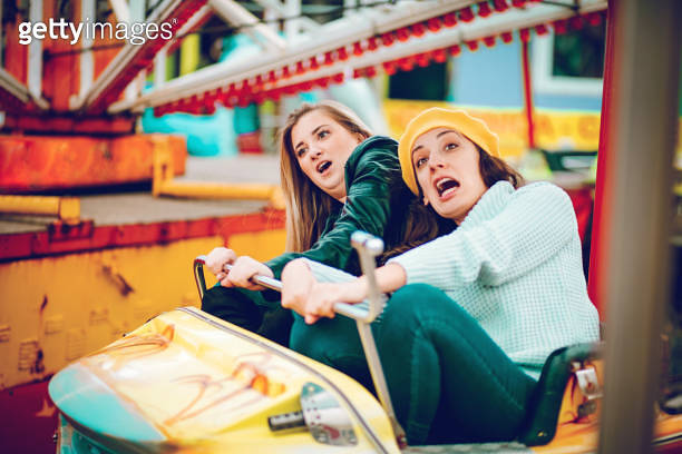 Two friends riding amusement park ride 이미지 (1136444639) - 게티이미지뱅크