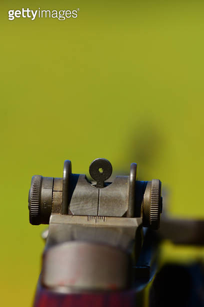 Narrow depth of field macro shot of WWII rifle sight with defocused gun ...