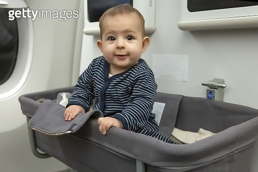 Baby in special bassinet seat in airplane. Have fun during the fly and ...