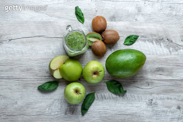 Fresh green food on a light table. Avocados cucumbers cabbage apples ...