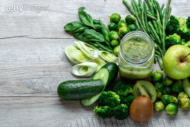 Fresh green food on a light table. Avocados cucumbers cabbage apples ...