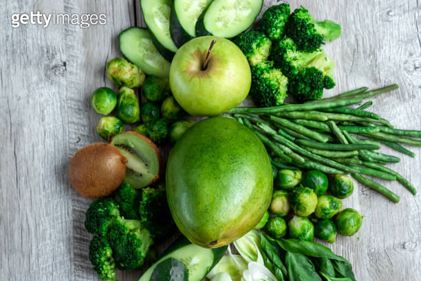 Fresh green food on a light table. Avocados cucumbers cabbage apples ...