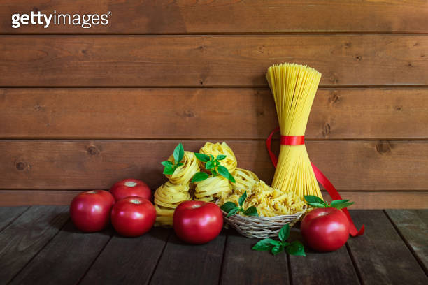 Different kinds of raw pasta, red ripe tomatoes and green basil leaves ...