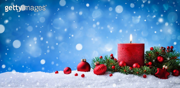 Christmas or advent candle, fir branches and decorations in snow ...
