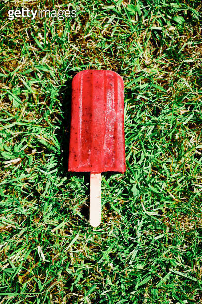 red berry fruit smoothie iced lolly on a garden lawn in bright sunshine ...