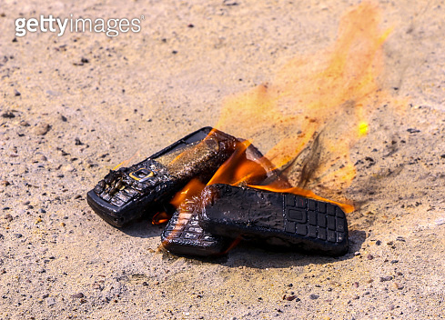burnt mobile phones on textural concrete background. Concept: Danger of ...