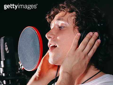 Male vocal artist with curly hair singing alone. Young handsome singer ...