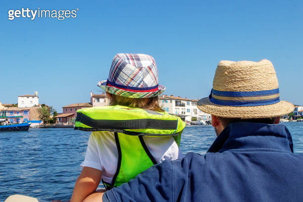 Back view of father and son in straw hats enjoying Port Grimaud ...