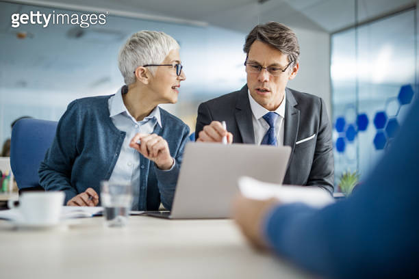 Two managers talking while working on laptop on a meeting in the office ...
