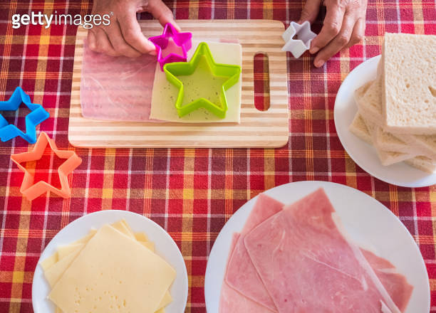 Two human hands preparing ham and cheese in shape of a star for a ...