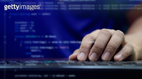 close up programmer man hand typing on keyboard at computer desktop for input coding language to ...