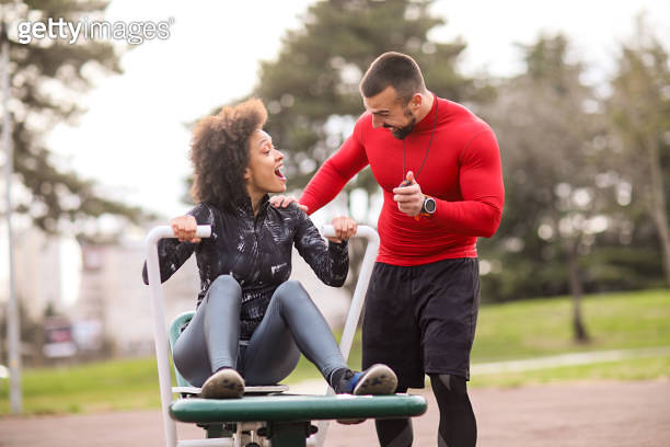 Muscular personal coach encouraging a female athlete and showing her ...