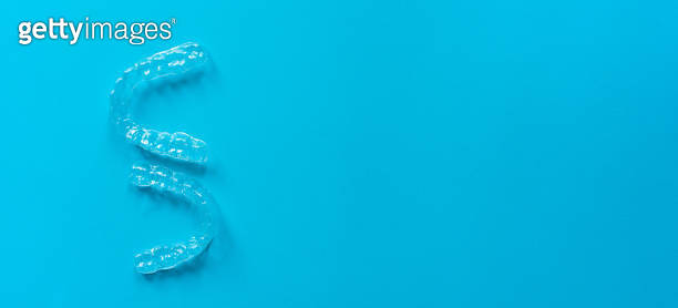 close up top view of dental aligner retainer (invisalign) on blue color ...