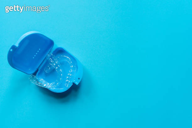 close up top view of dental aligner retainer (invisalign) on blue color ...