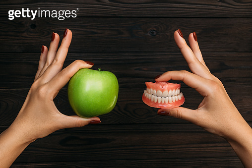 False teeth denture against green granny smith apple. Dental prosthesis ...