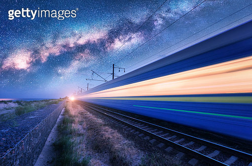 High speed train in motion and Milky Way at starry night. Industrial ...