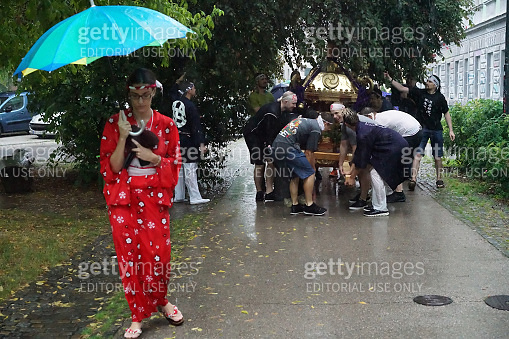 Woman in red kimono in front of the Mikoshi on street, during heavy ...