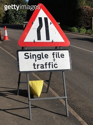 Road traffic sign by the side of a road that says single file traffic ...