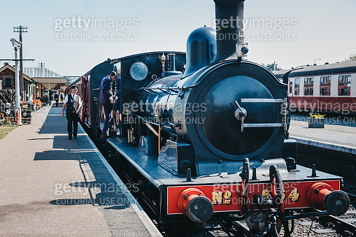 Staff walking on platform next to The Poppy Line steam train ...