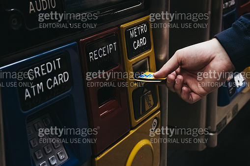 Male hand puts Metro Card into a top up machine at a subway station in ...