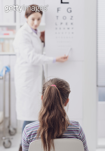 Oculist testing a young patient's eyesight using an eye chart 이미지 ...