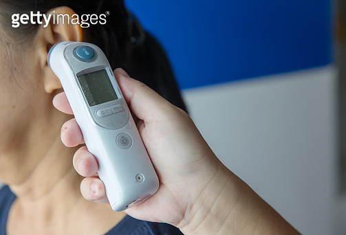 Doctor checking patient's temperature in the ear with Tympanic ...