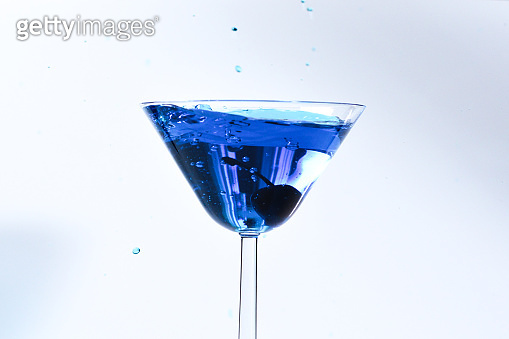 Cocktail with blue liquid in glass. Glass with blue water pouring with ...