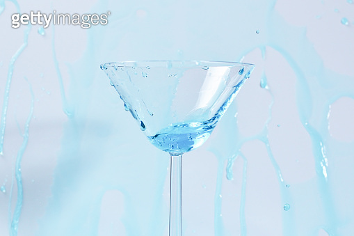 Cocktail with blue liquid in glass. Glass with blue water pouring with ...