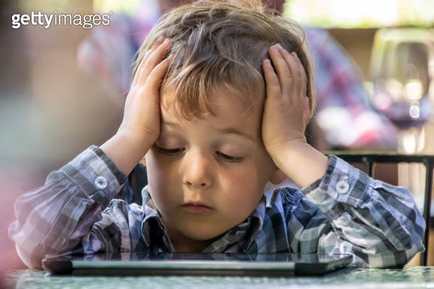 Desperate Three years old child boy looking at his electronic tablet ...