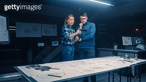 Two Young Software Development Engineers Talk and Use Smartphone with ...