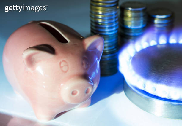 The piggy bank near the blue flame of a natural gas stove. Symbolic ...