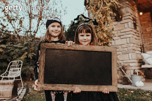 Two little girls, in Halloween costumes, holding a blank board 이미지 ...
