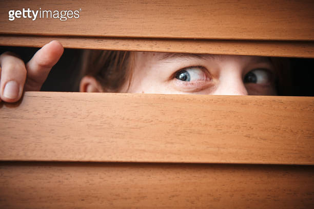 Suspicious and scared woman peeps sideways through venetian blind 이미지 ...