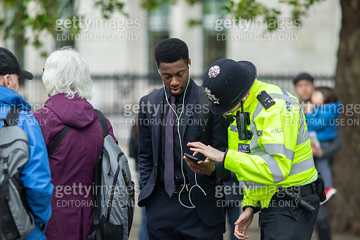 Friendly metropolitan policeman helping a smart young black guy with ...