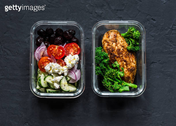 Two healthy balanced lunch boxes with greek salad, baked chicken breast ...
