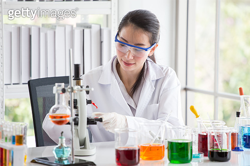 asian woman Scientist Research and Reaction woman pouring a liquid in a ...