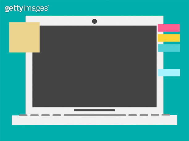 A computer with stickers glued to the screen against a turquoise wall ...