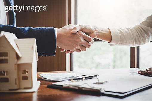 Real estate agent and customers shaking hands together celebrating ...