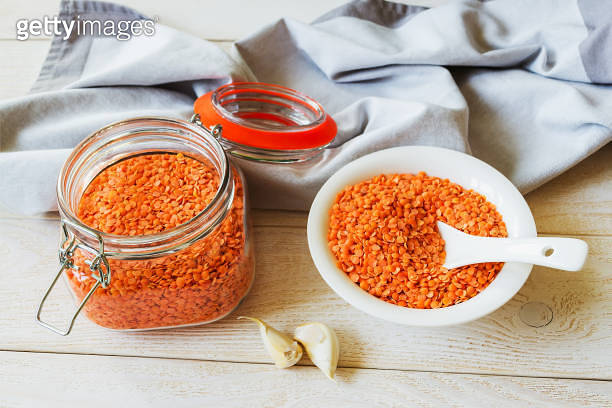 Dried red lentils in a glass clip top jar and bowl on white rustic ...