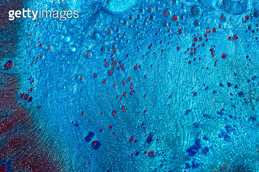 Macro shot suspension of particles in a colored emulsion over backlit ...