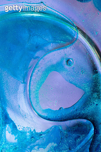 Macro shot suspension of particles in a colored emulsion over backlit ...