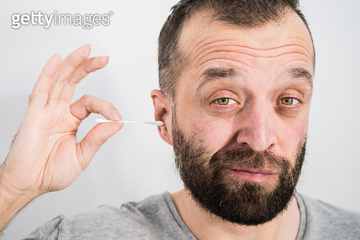 Man removing wax from ear using Q-tip (1140012194) - 게티이미지뱅크