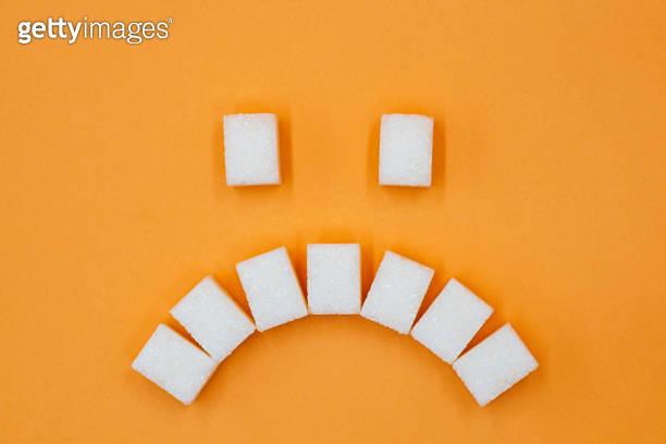 Sad face symbol, composed of cubes of sugar. Concept of sugar leading ...