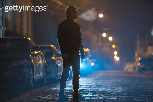 The man stand on the stone road. Evening night time. Telephoto lens ...