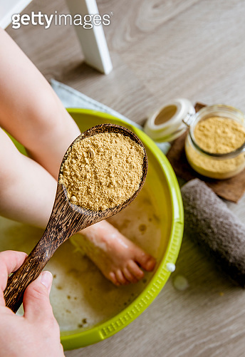 Child taking a healing warming foot bath with mustard powder, adding ...