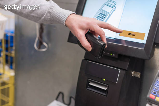 Man paying at the self-service counter using the touchscreen display ...