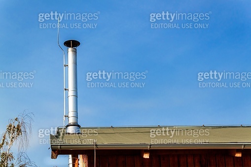 New metal chimney pipe on wooden house. Stainless steel chimney on ...