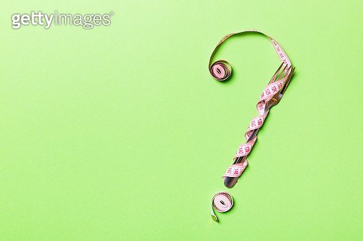 Top view of question mark made of fork and measuring tape on green ...